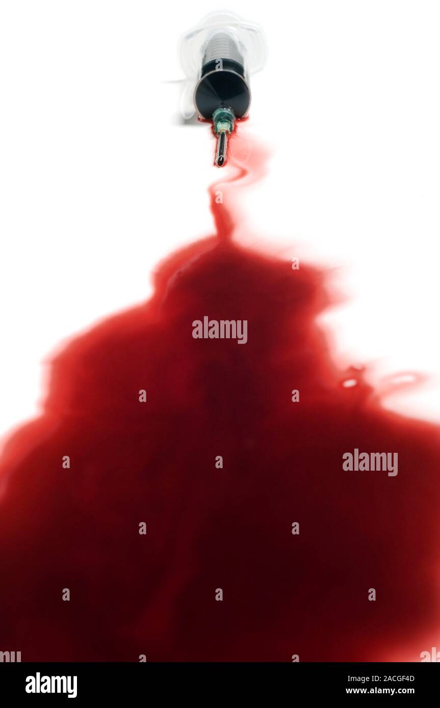 Syringe with red liquid spreading through water. The syringe (upper ...