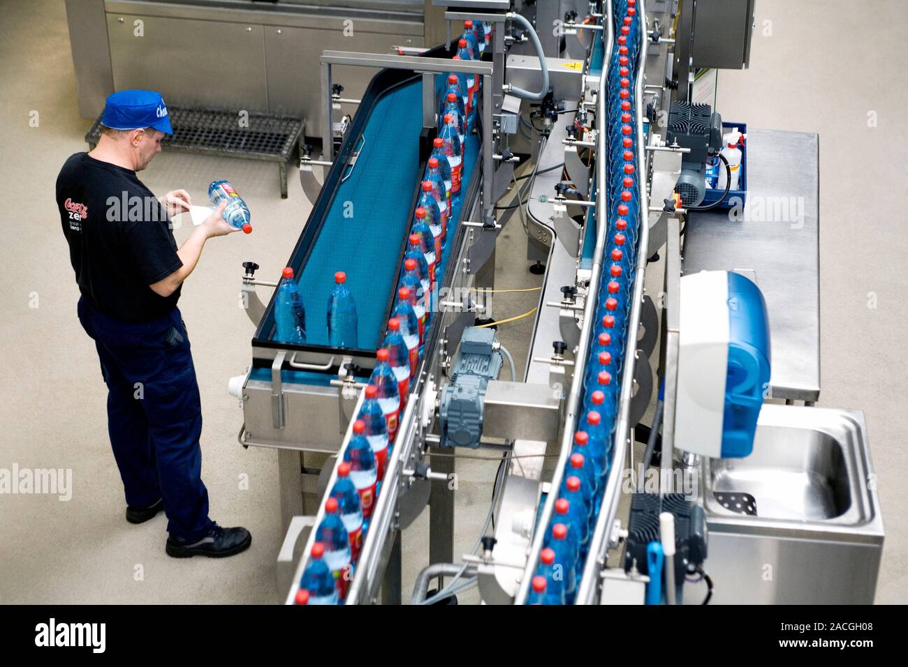 Bottled water production line. Worker labelling bottles of ...