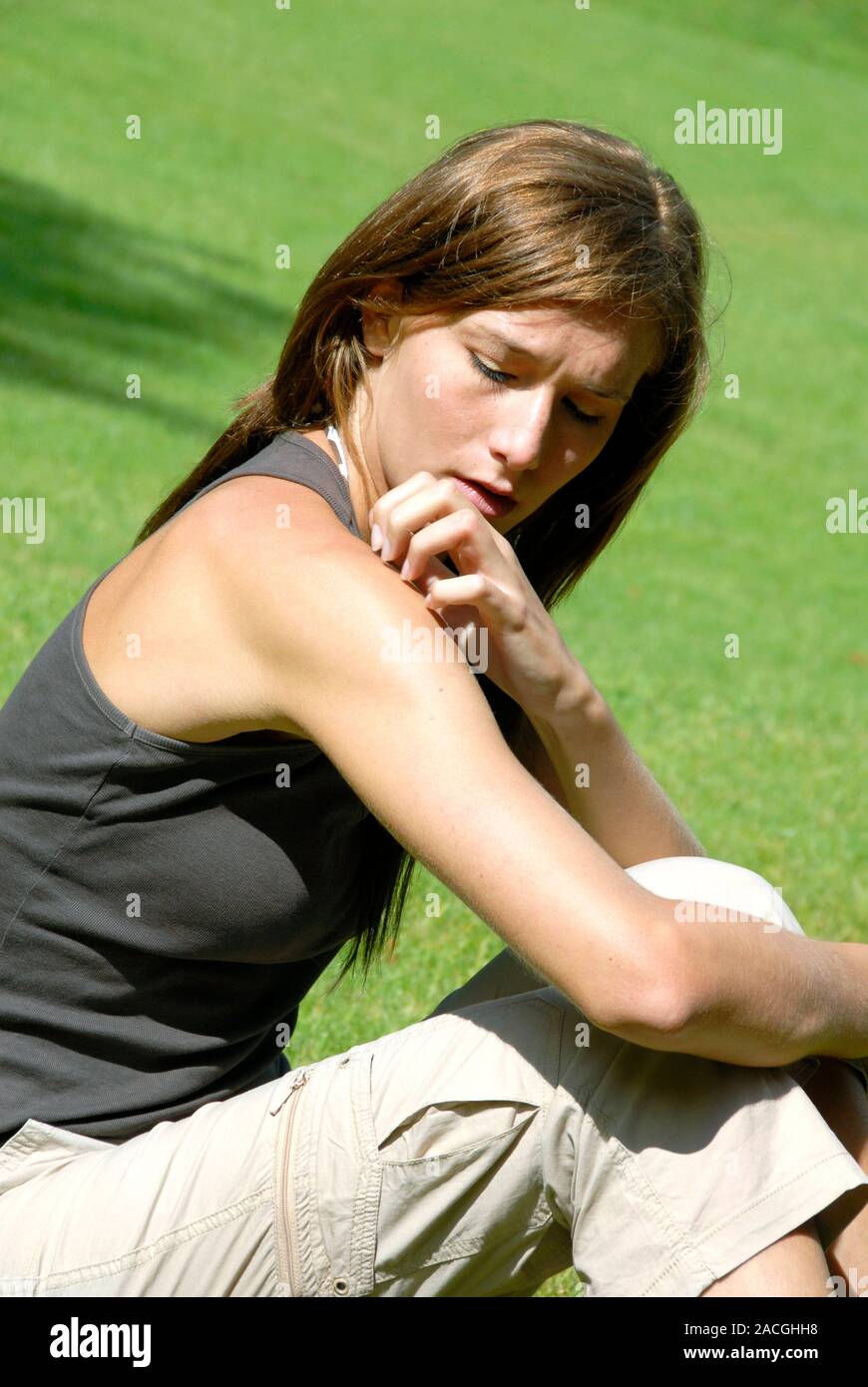 Women scratching. Young women scratching an itch on her shoulder whilst ...