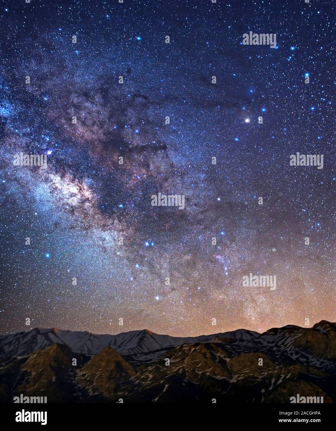 Milky Way over mountains. Bands of dust and glowing nebulae are seen ...