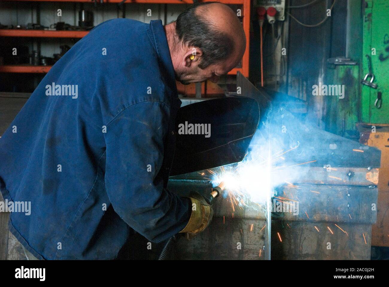 Metal workshop production line. Worker welding metal pieces together ...