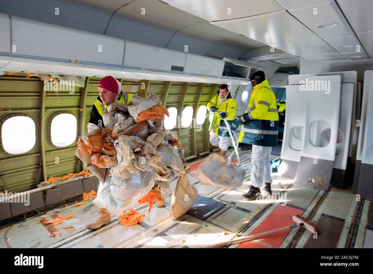 Aircraft dismantling. Workers removing the cabin insulation from a ...