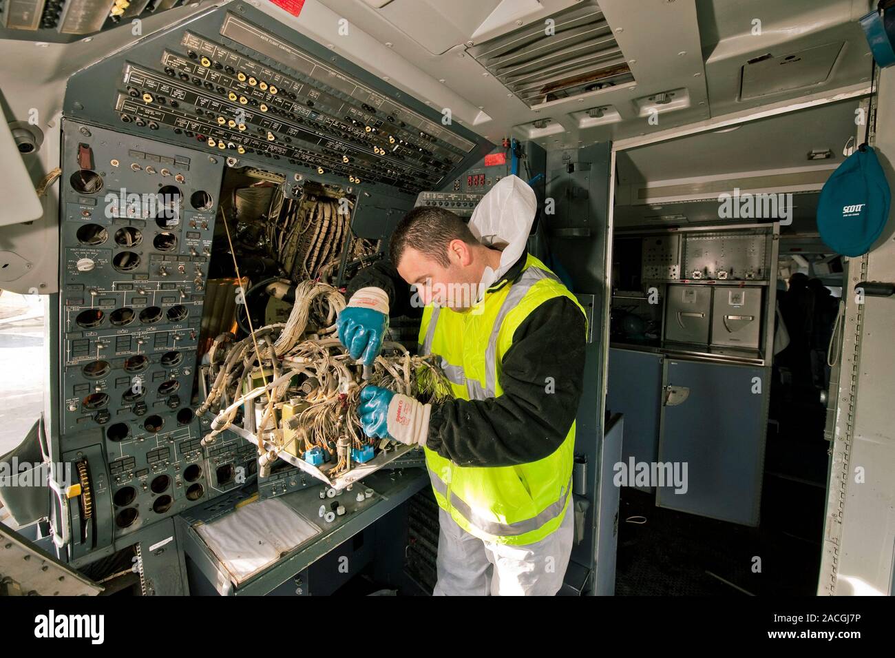 Aircraft dismantling. Worker removing the instrument panels from the ...