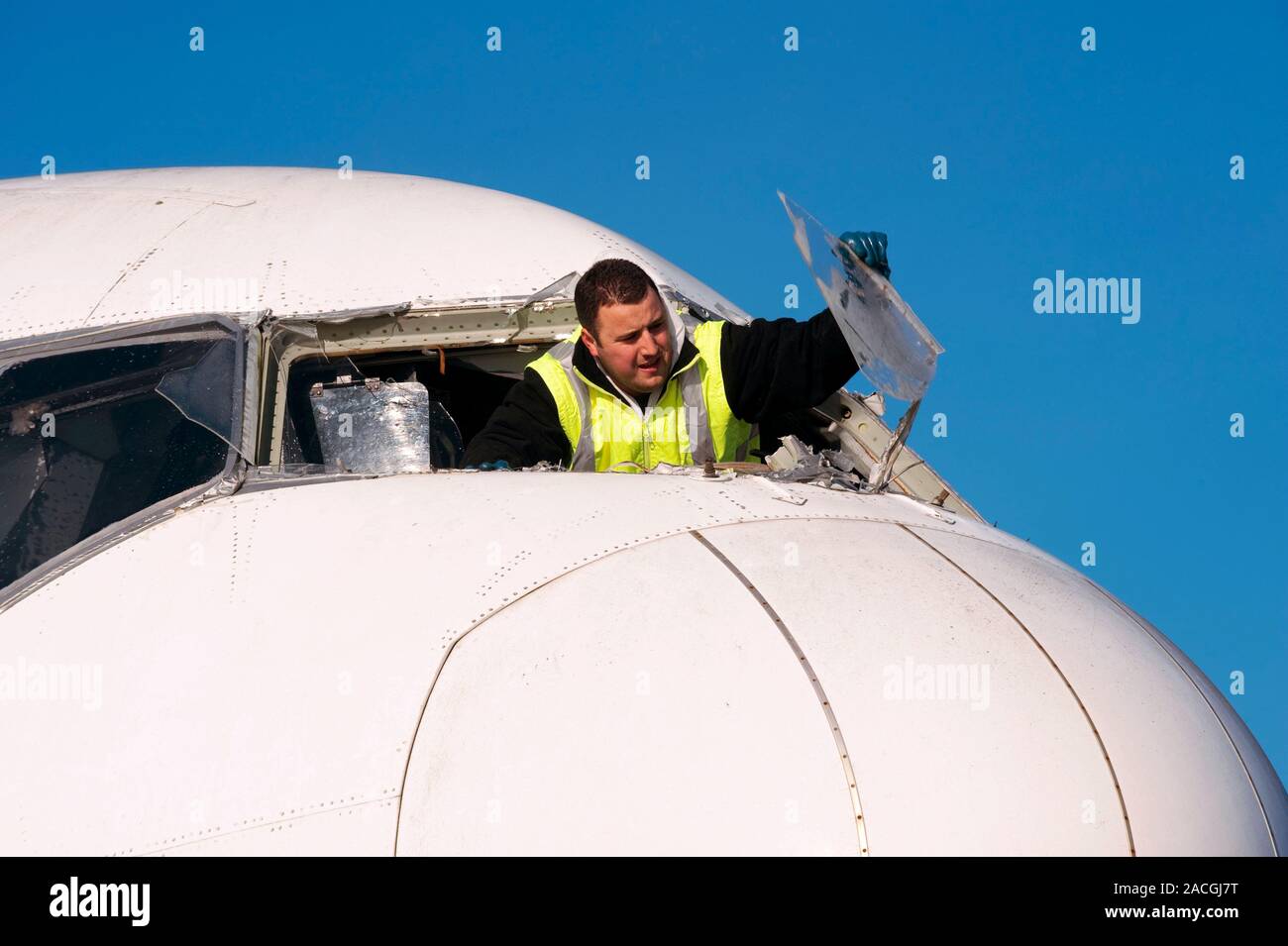 Aircraft dismantling. Worker removing the windows from the cockpit of a ...