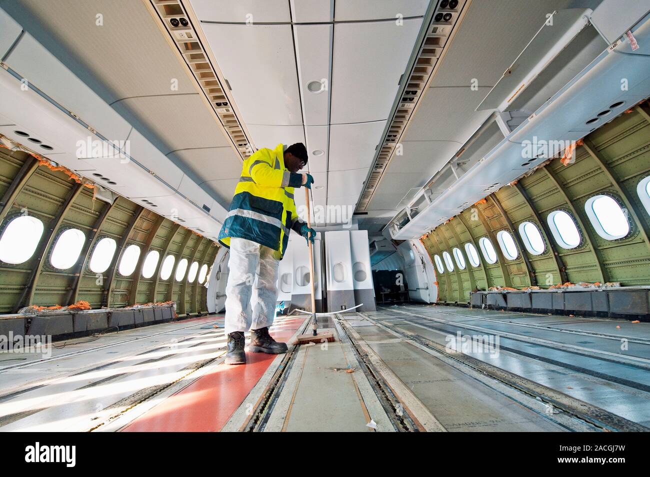 Aircraft dismantling. Worker sweeping the cabin of a passenger plane ...