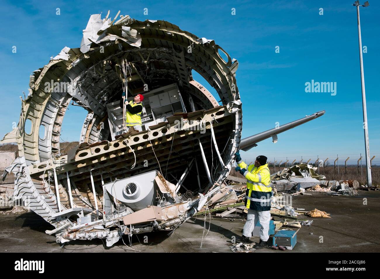 Aircraft dismantling. Workers dismantling a section of fuselage from a ...