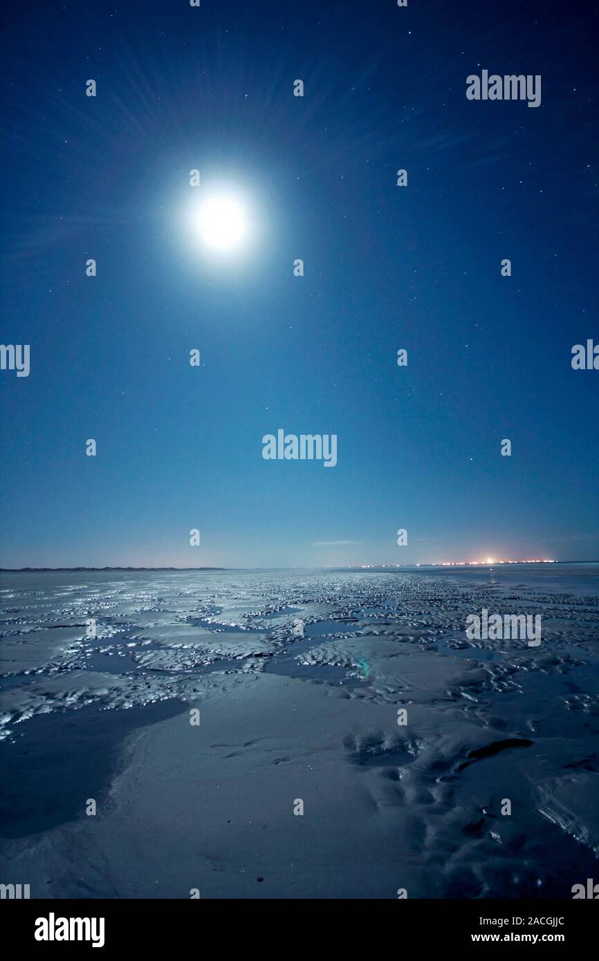 Low tide at night. Exposed sand shows the patterns made by the ebb and ...