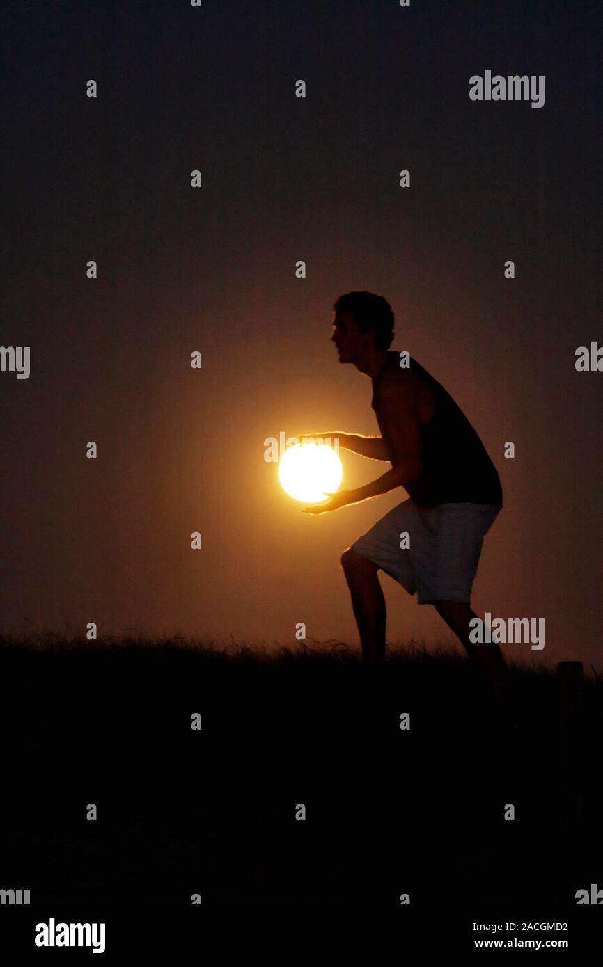 Playing with the Moon. Basketball player standing in front of a full ...