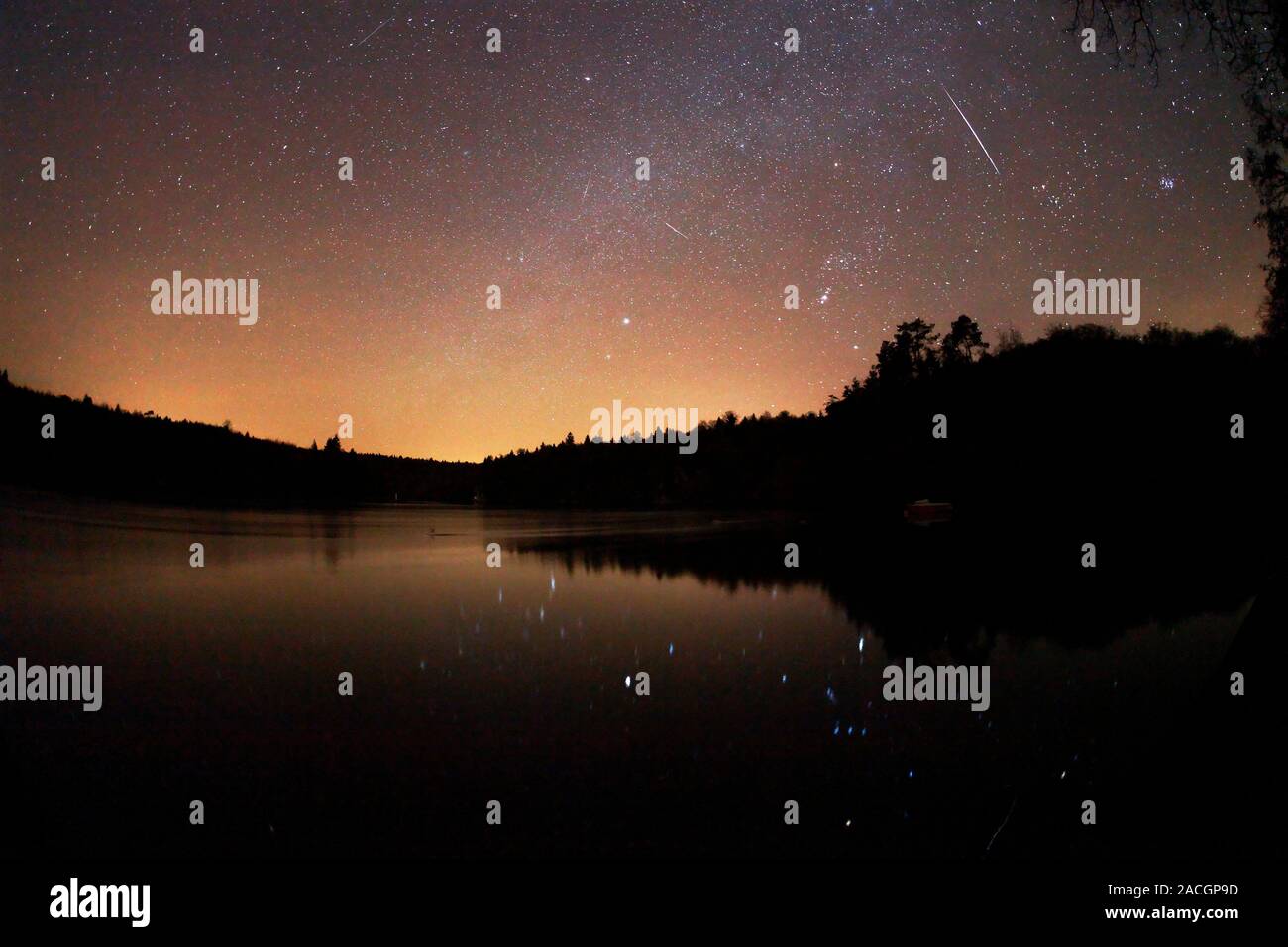 Meteor shower. Geminid meteors appearing in the sky over a river. The ... Meteor shower. Geminid meteors appearing in the sky over a river. The ...