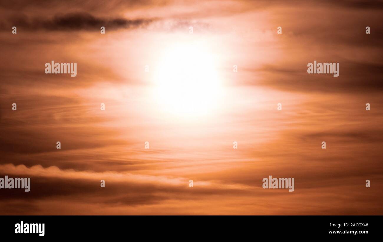 Sun shining through clouds at sunset Stock Photo - Alamy
