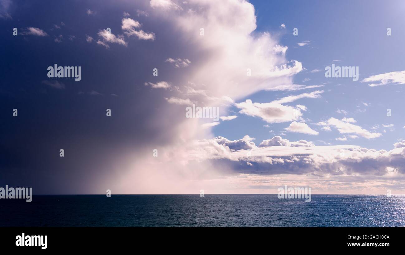 Menacing storm clouds illuminated by sunlight taking over the blue sky ...