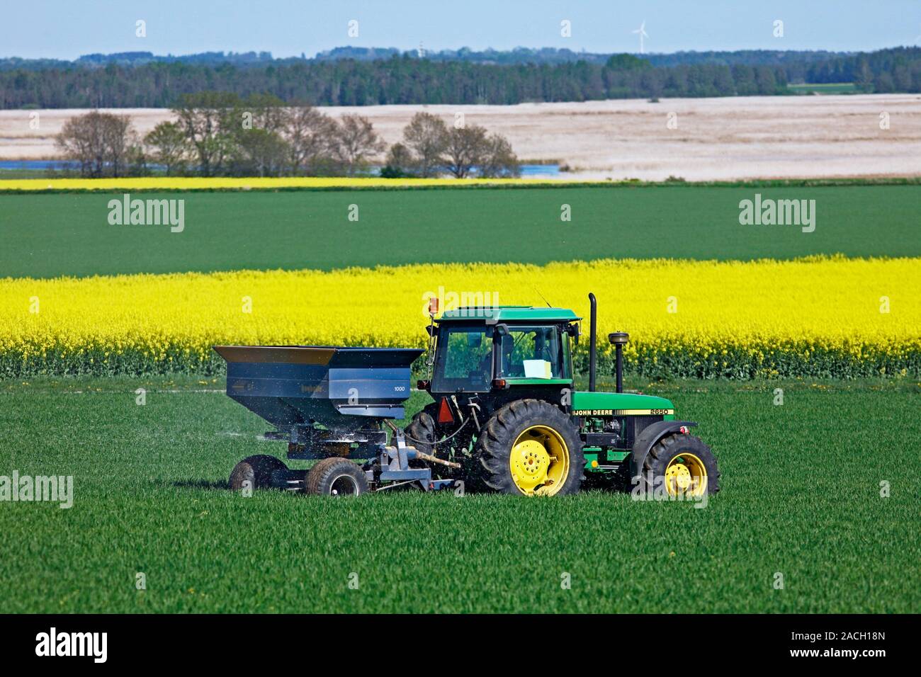 Fertilising. Tractor spreading fertiliser on a field. Photographed in ...
