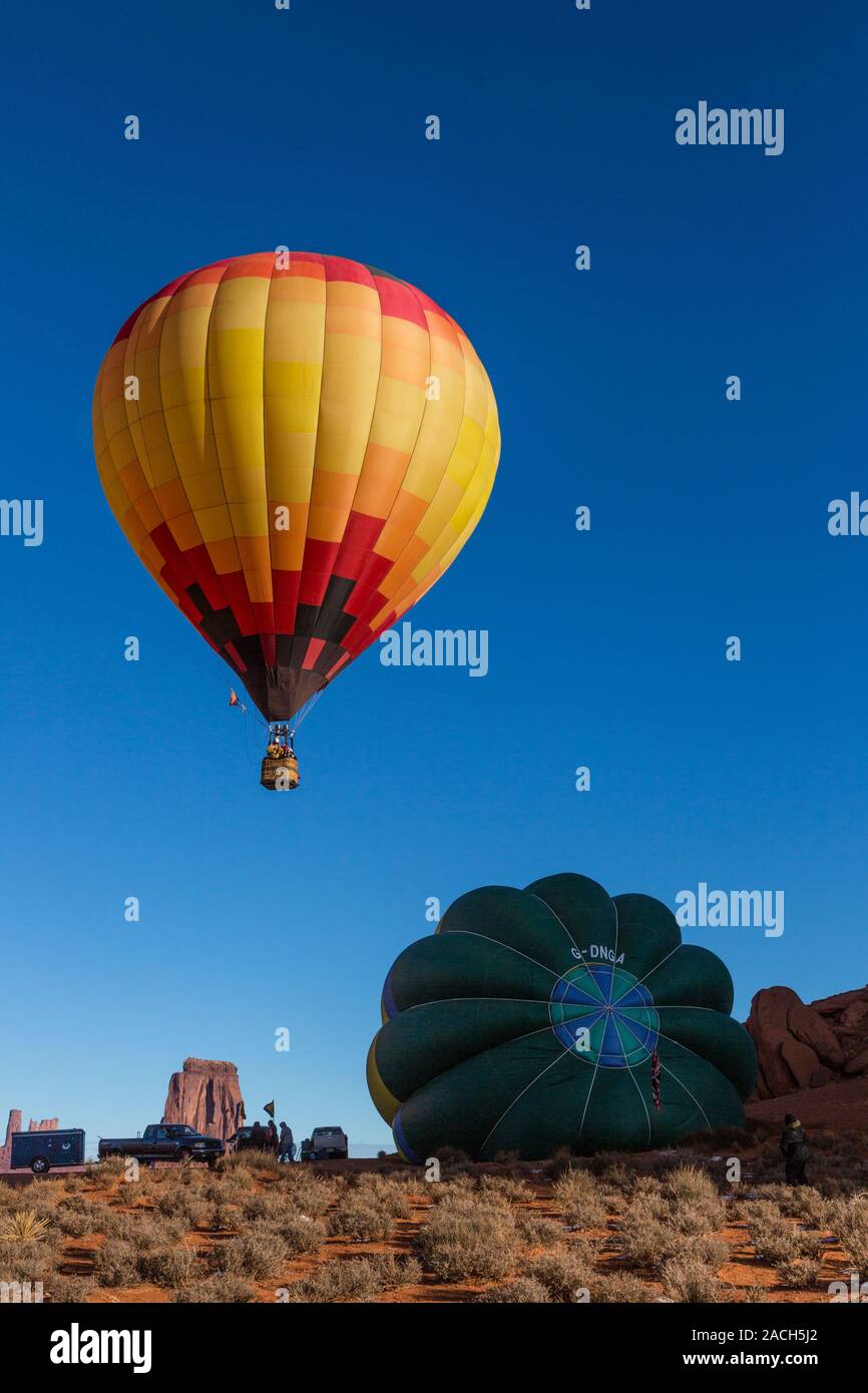 A hot air balloon rises in the early morning sky in the Monument Valley ...