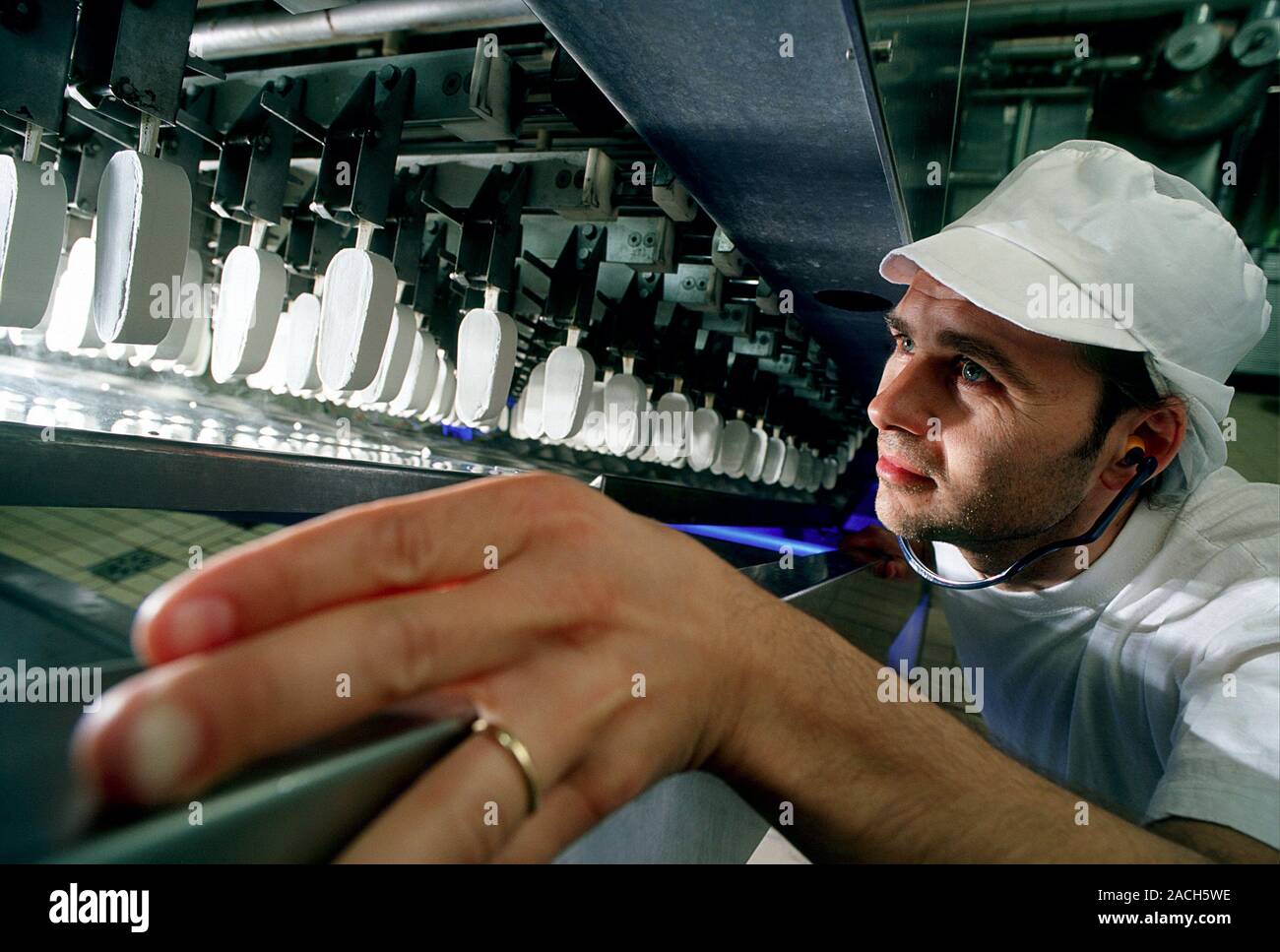 Ice cream factory. Worker checking ice creams that are about to be ...