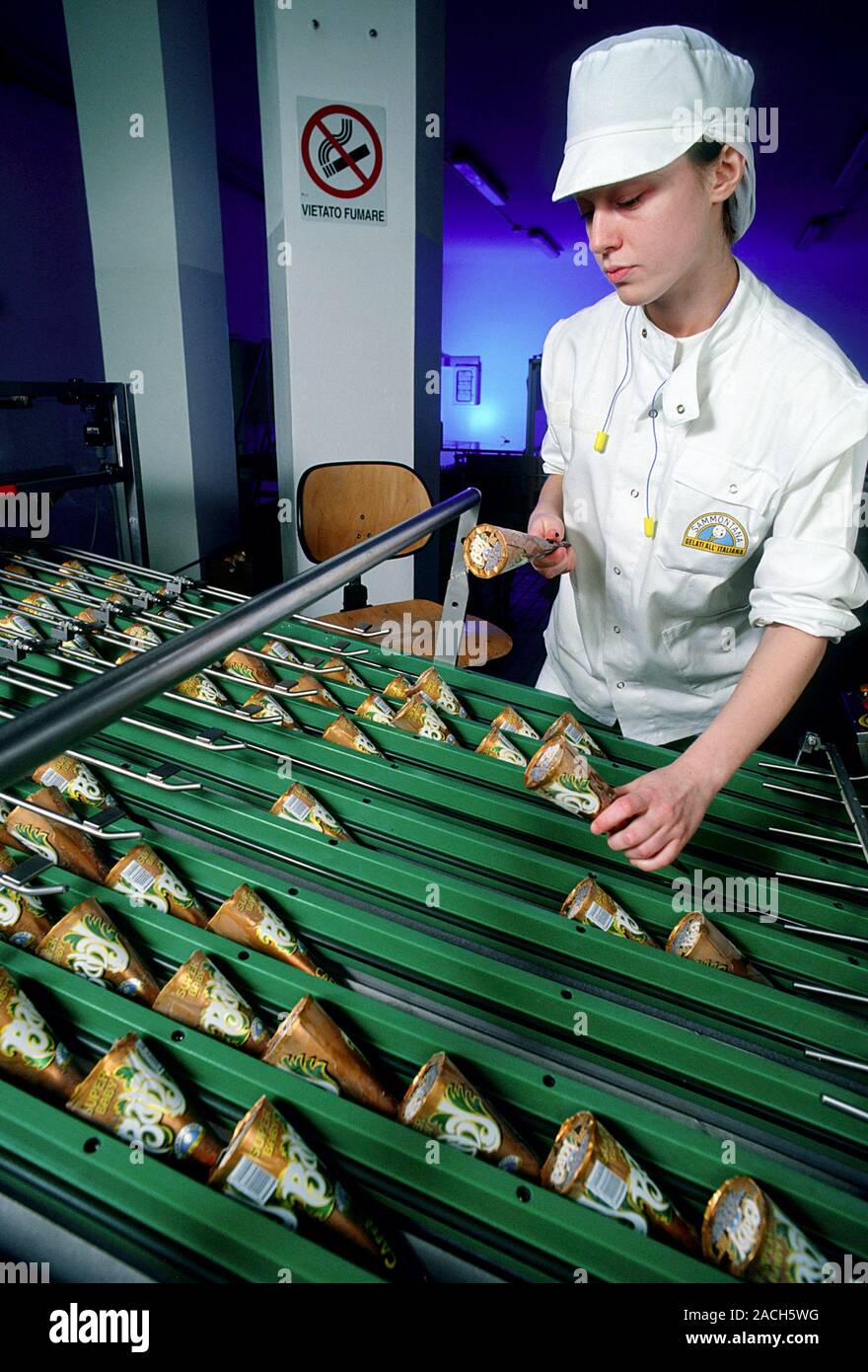 Ice cream factory. Worker checking finished ice cream cones at an ...