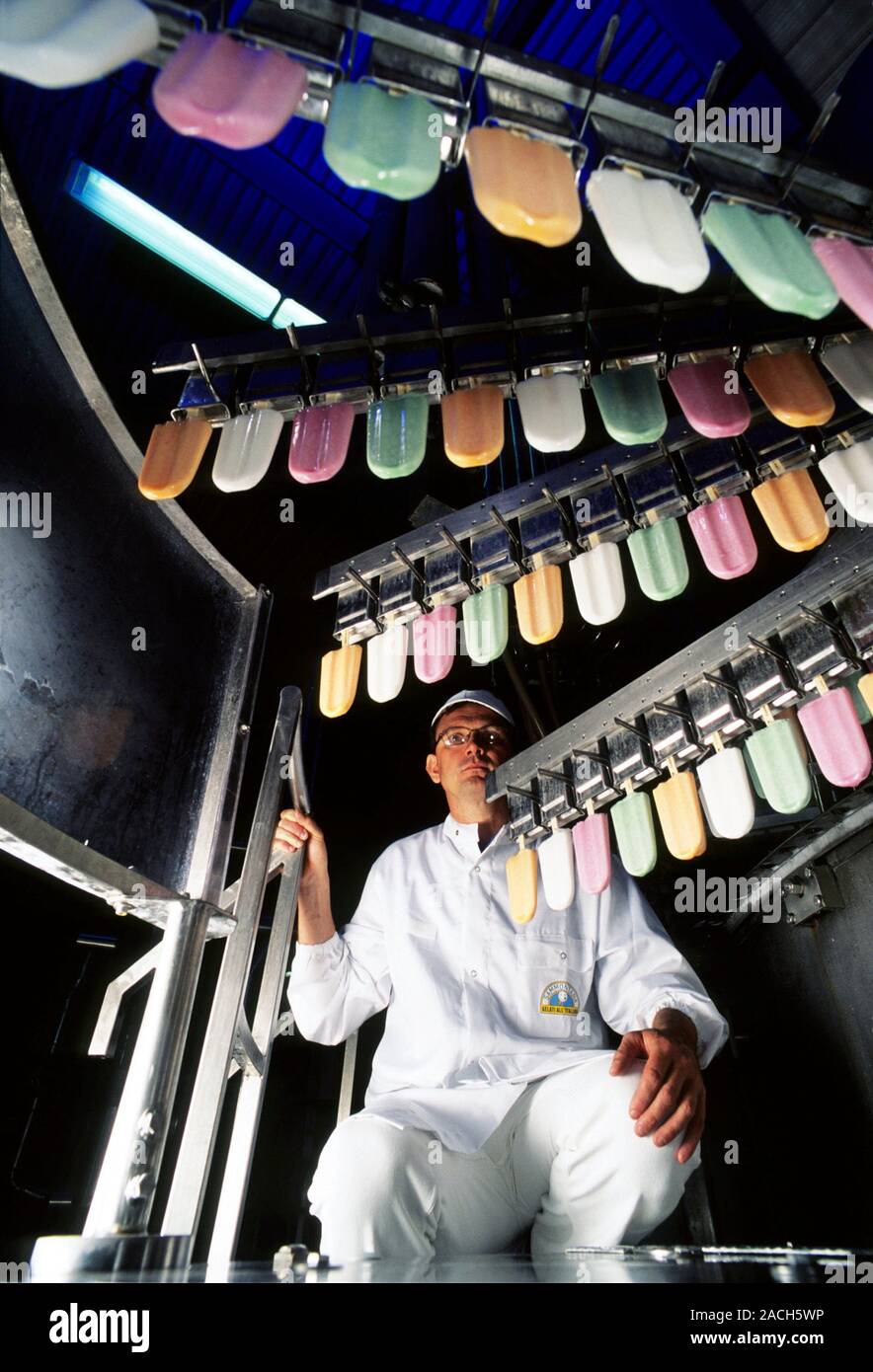 Ice cream factory. Worker inspecting ice lollies on the production line ...