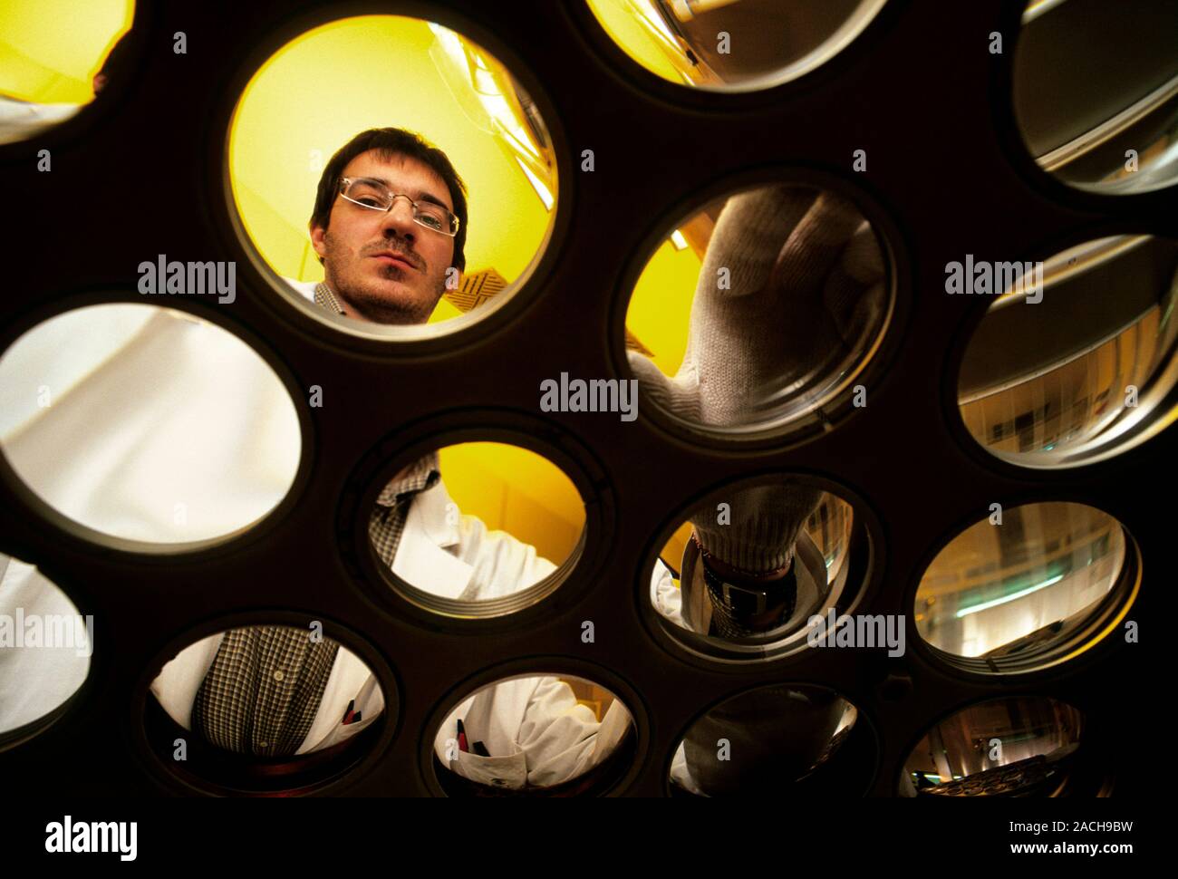 Eyeglasses manufacturing. Technician inspecting plastic lens blanks ...