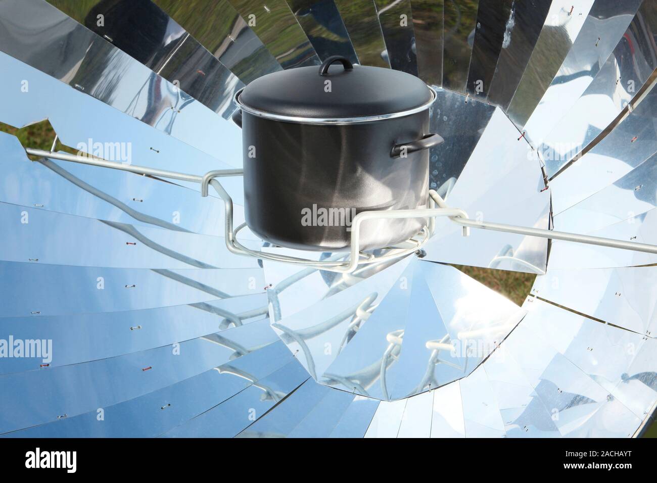 Parabolic solar cooker. Cooking pot being heated on a parabolic solar ...