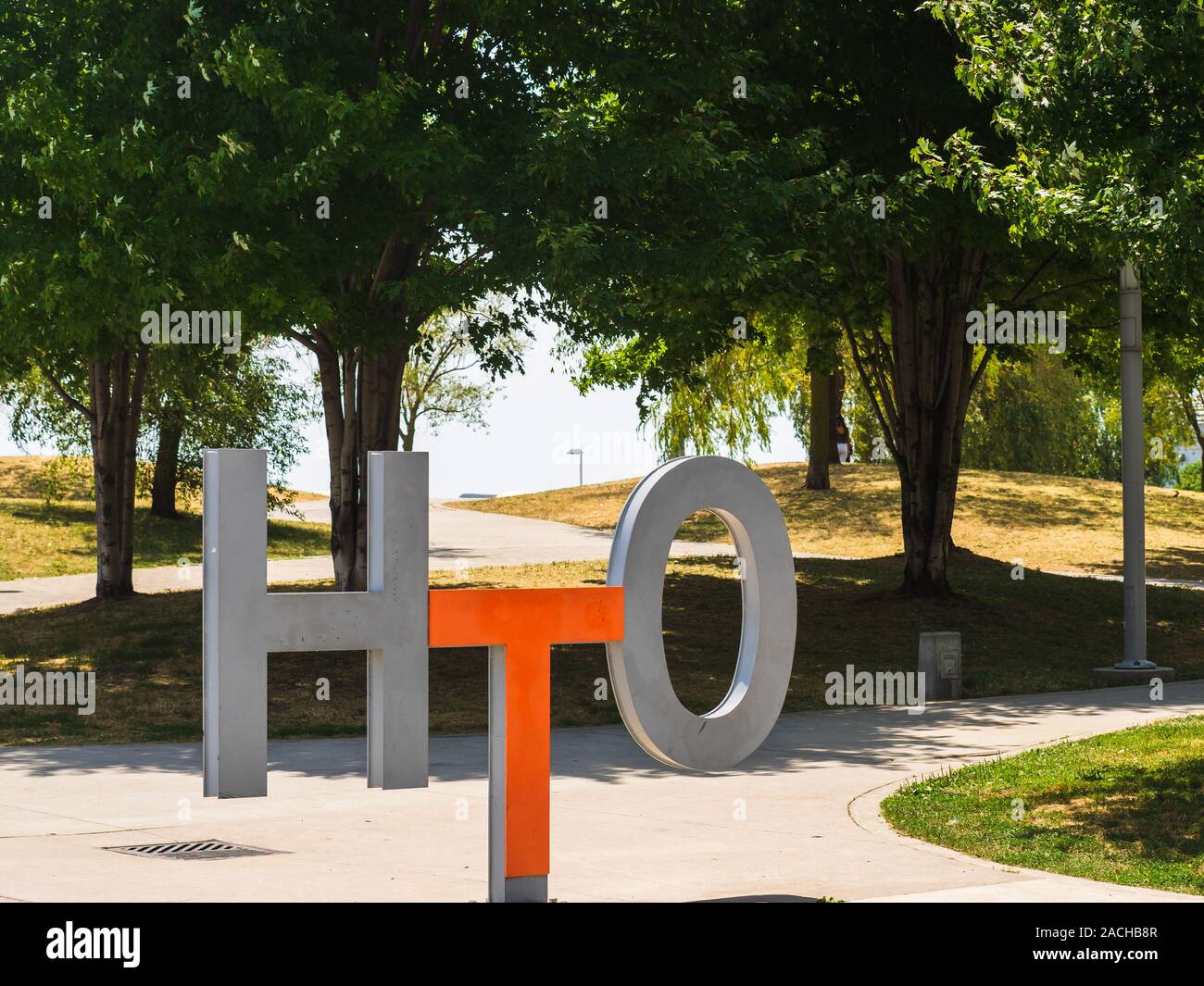 Trees with green leaves overhang the artsy HTO park entrance sign Stock ...