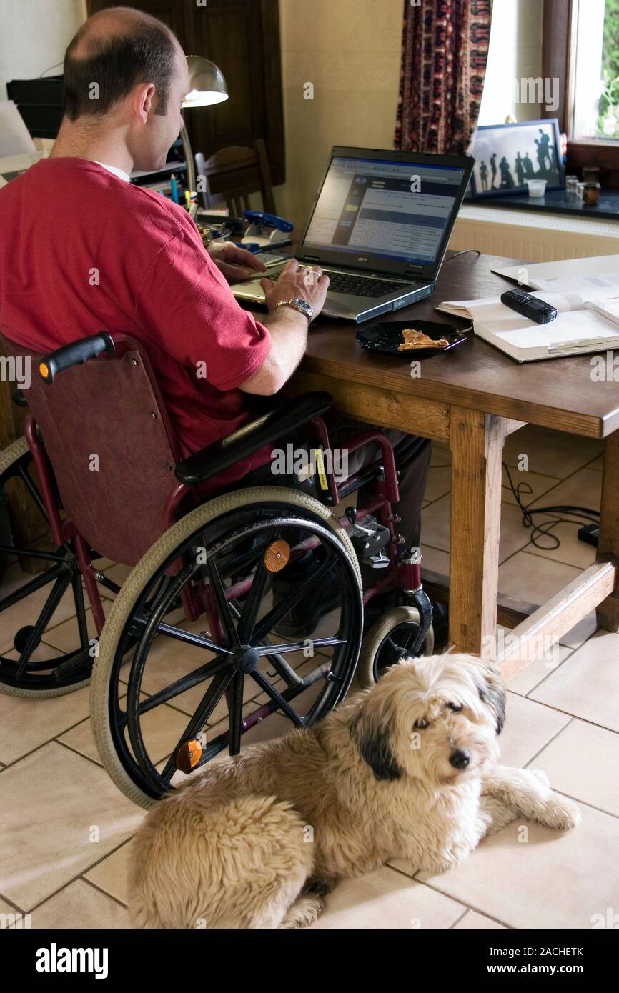 Disabled computer user. Disabled man in a wheelchair using a laptop ...