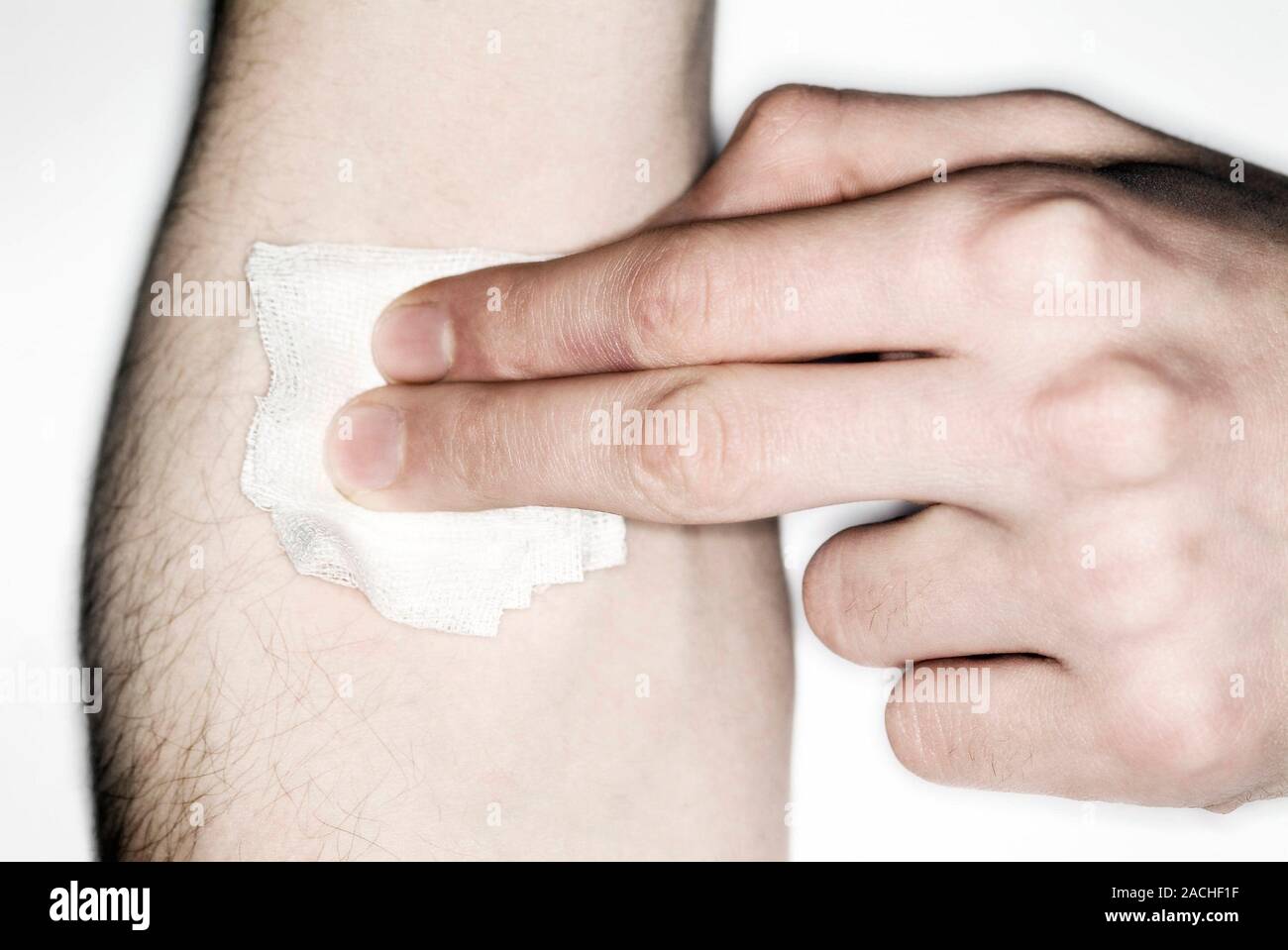 Blood test. Patient holding a dressing on their skin at the site where ...
