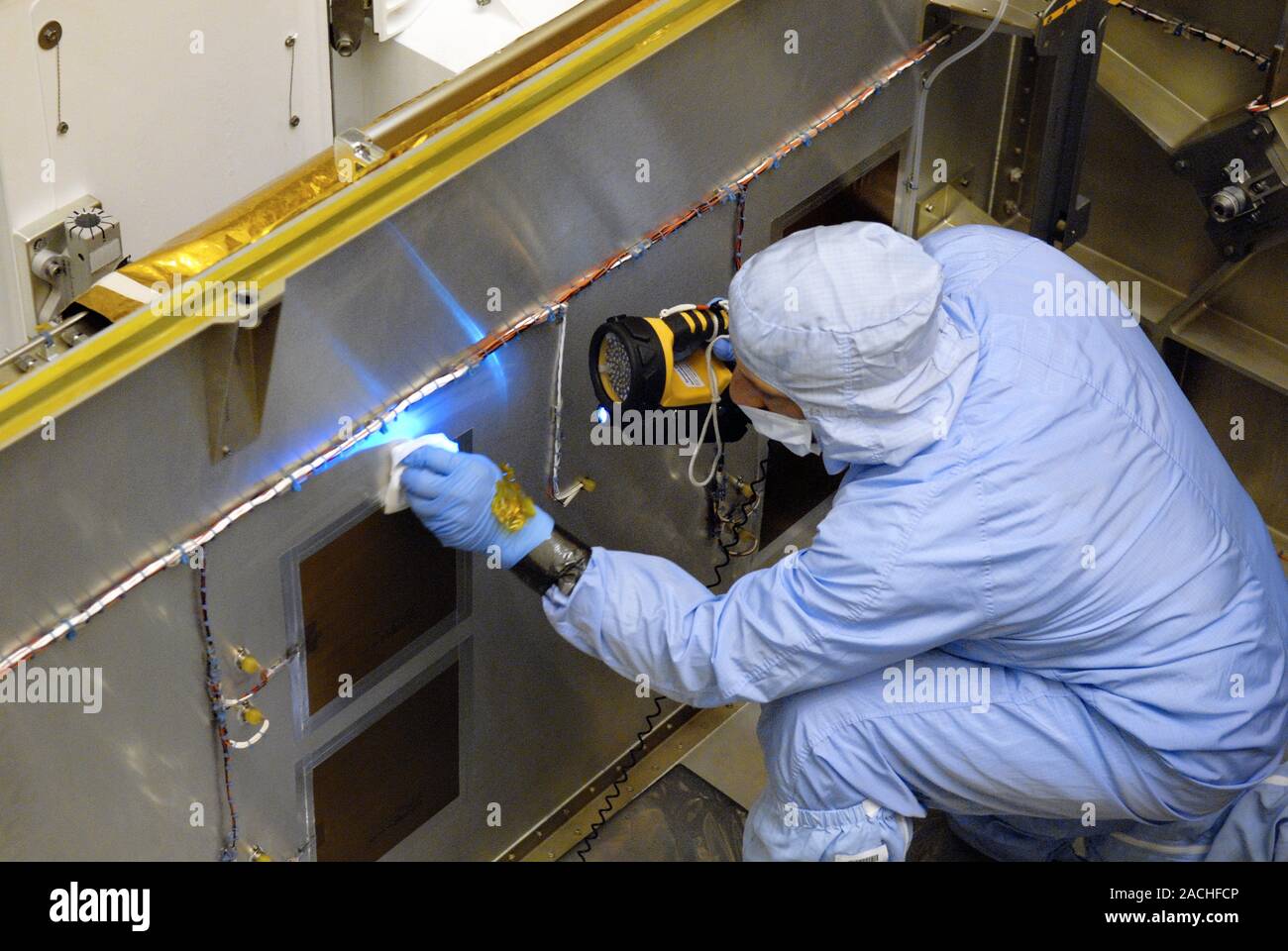 Cosmic Origins Spectrograph inspection. Clean room worker inspecting ...