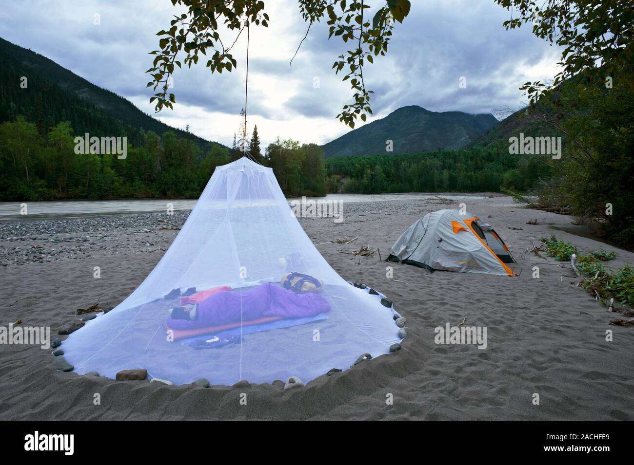 Sleeping under a mosquito net. The net has been secured by stones ...