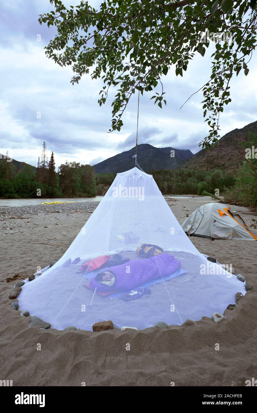 Sleeping under a mosquito net. The net has been secured by stones ...