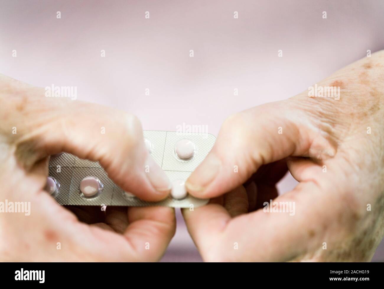 Aspirin-based cardiovascular pills. Elderly woman releasing a pill from ...