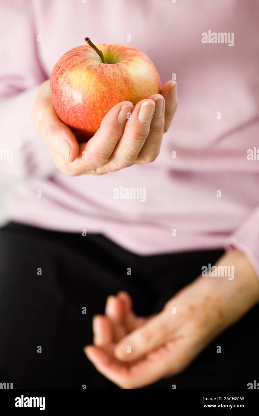 Holding an apple. Elderly woman holding an apple Stock Photo - Alamy