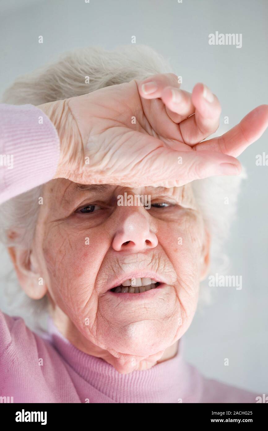 Raised temperature. Elderly woman holding the back of her hand to her ...