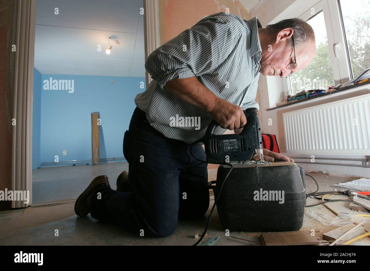 Construction worker using an electric saw to cut a piece of wood during ...