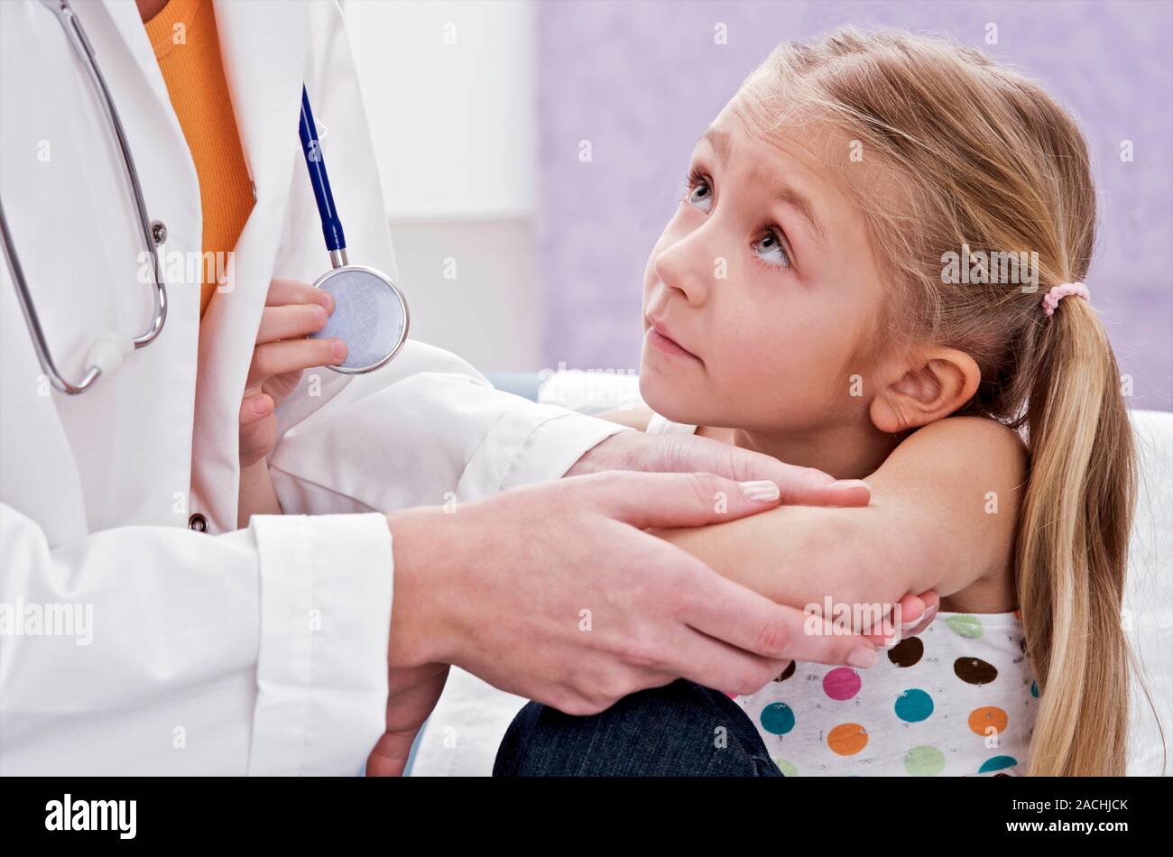Paediatric examination. Doctor checking a 7-year-old girl's arm during ...