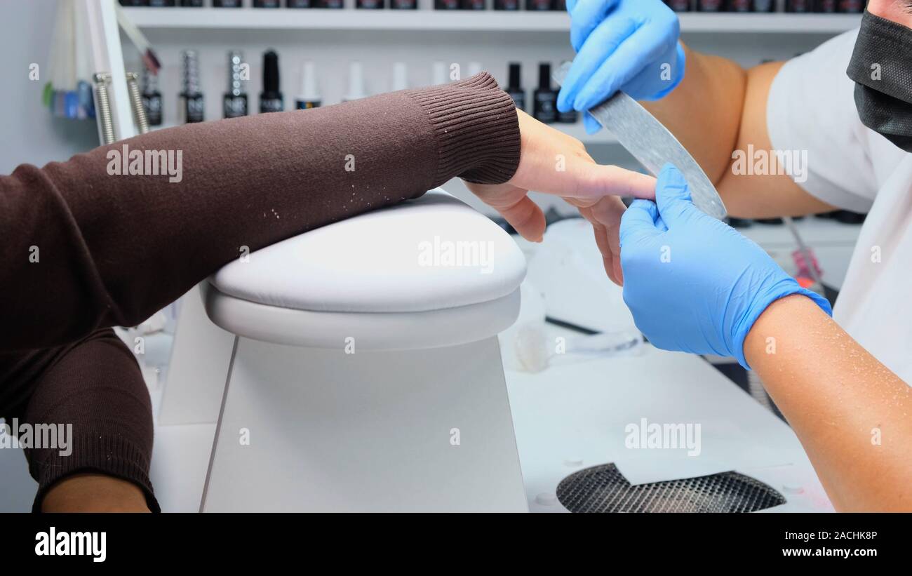 Manicurist files a nail with a nail file to a client. Manicure process ...