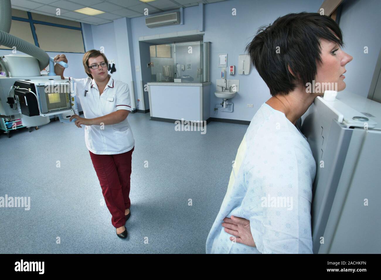 Chest X-ray. Radiographer (left) taking a chest X-ray of a female ...