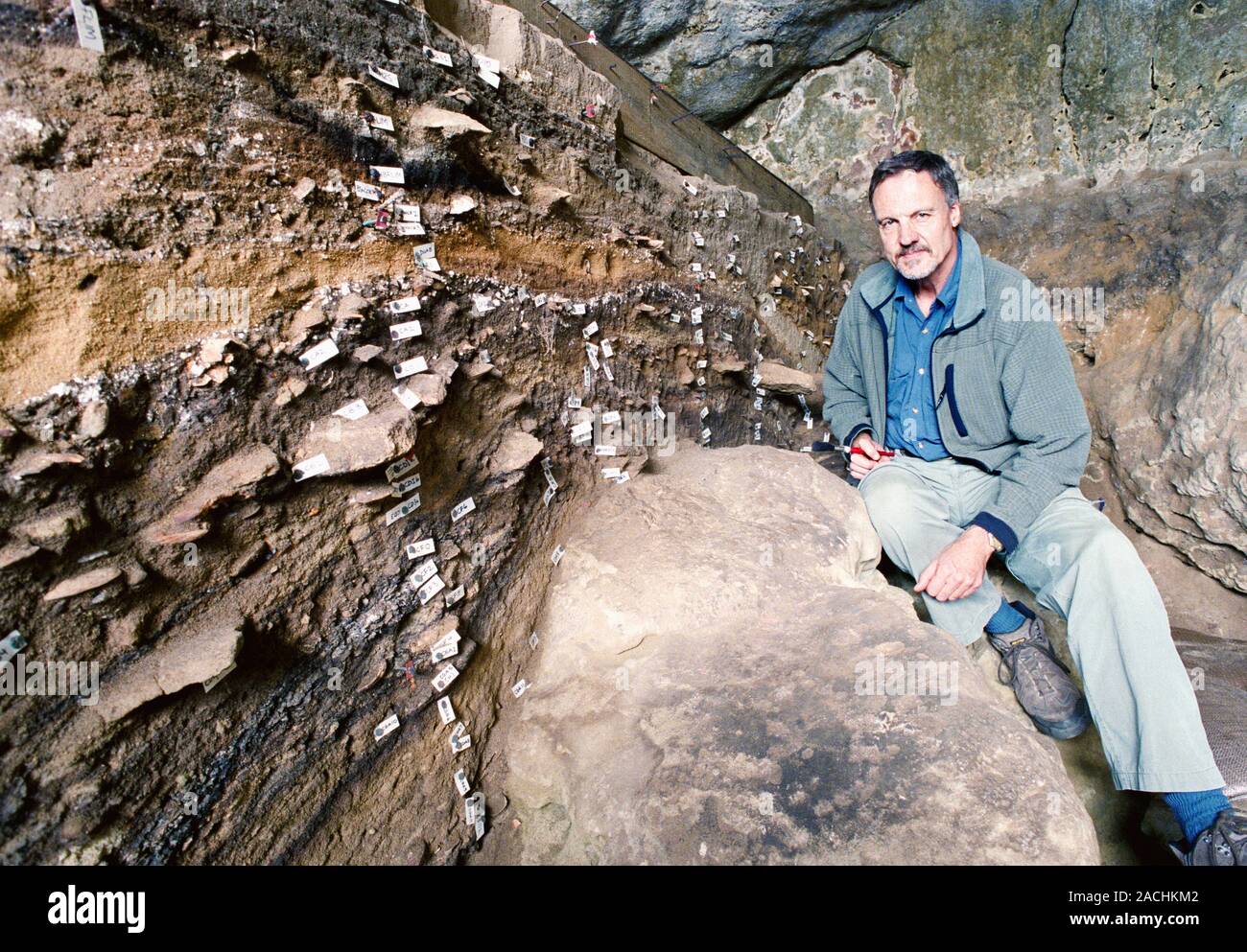 Archaeological excavation. Archaeologist sitting on a block of roof ...