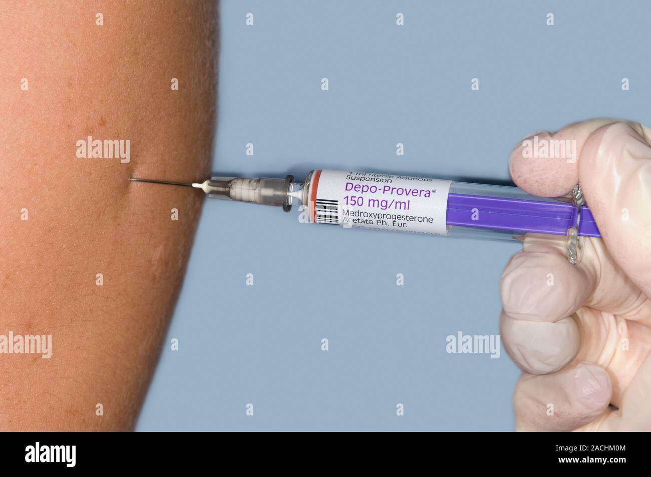 Gloved hand uses a syringe to inject Depo-provera contraceptive into ...