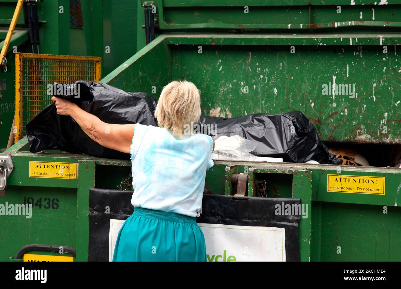 Recycling centre. Woman emptying refuse into a container at a recycling ...