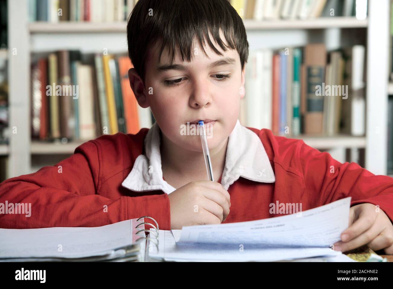Boy doing homework, concentrating with his pen held to his mouth Stock ...