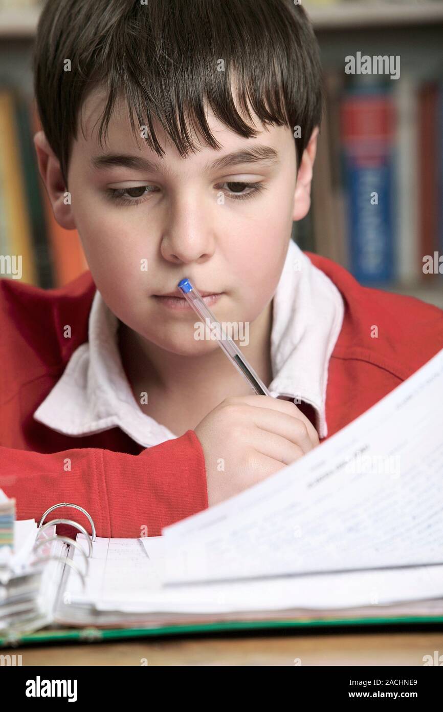 Boy doing homework, concentrating with his pen held to his mouth Stock ...