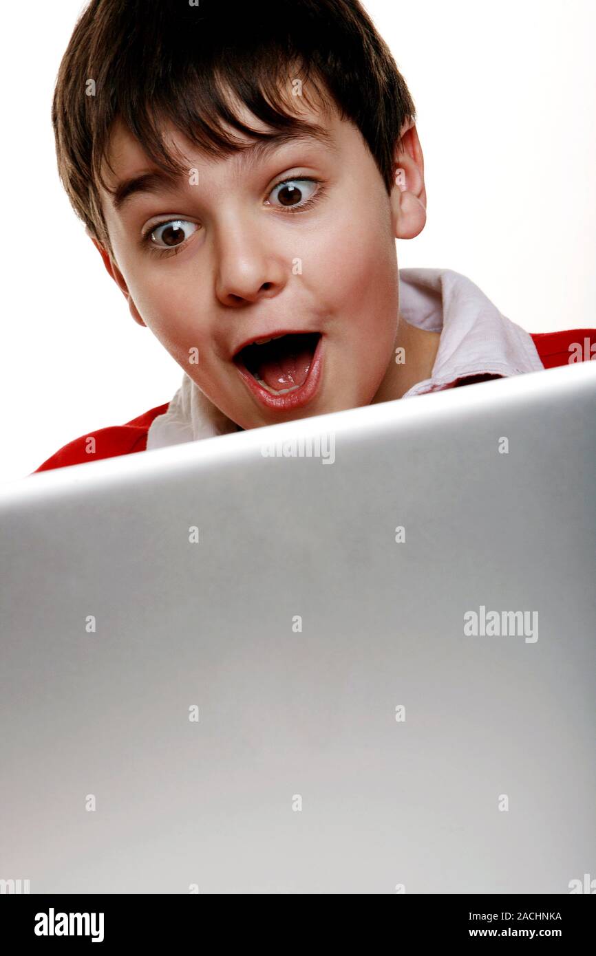 Boy using a laptop computer, with his mouth and eyes wide open in ...