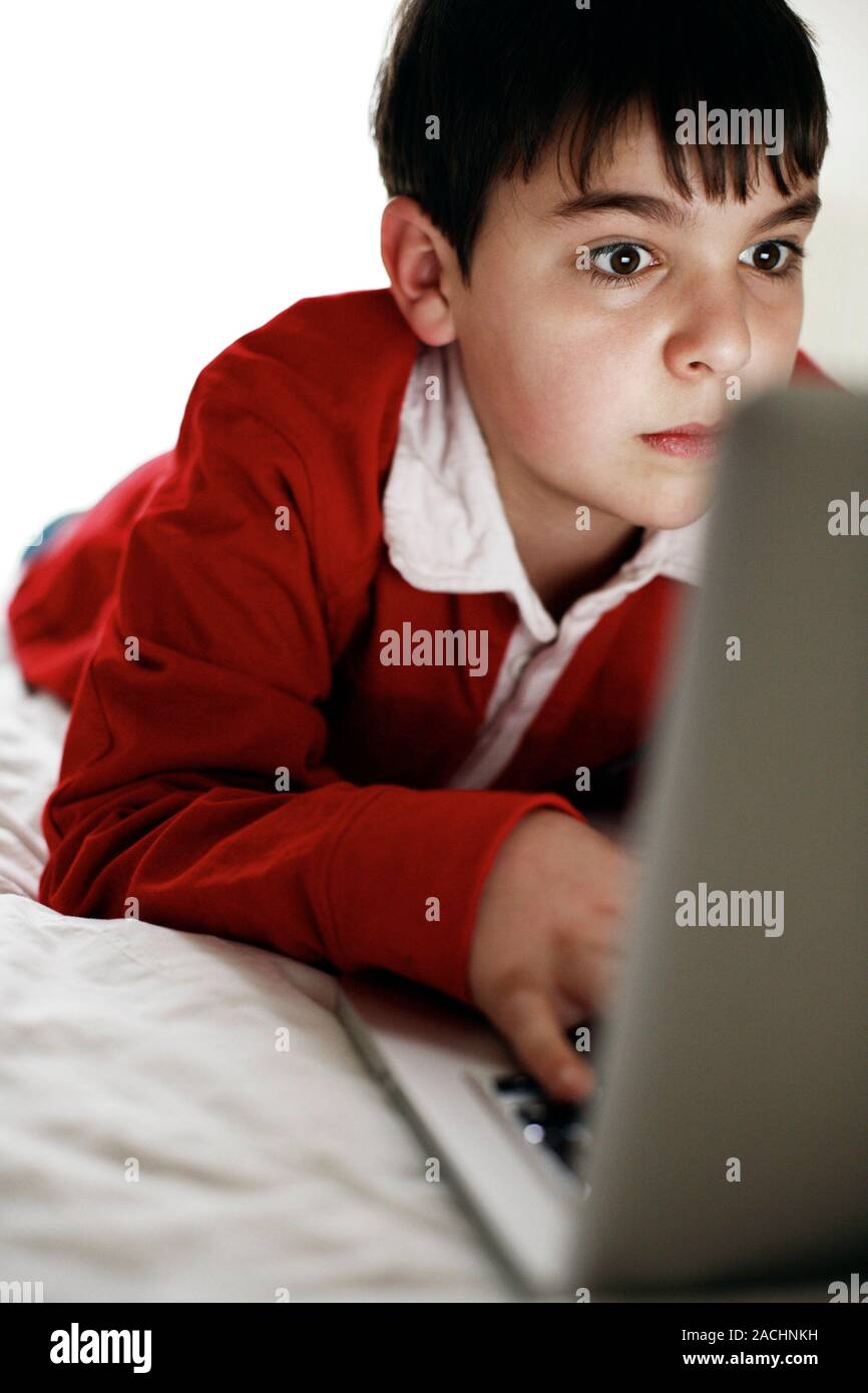Boy using a laptop computer while lying on his bed Stock Photo - Alamy
