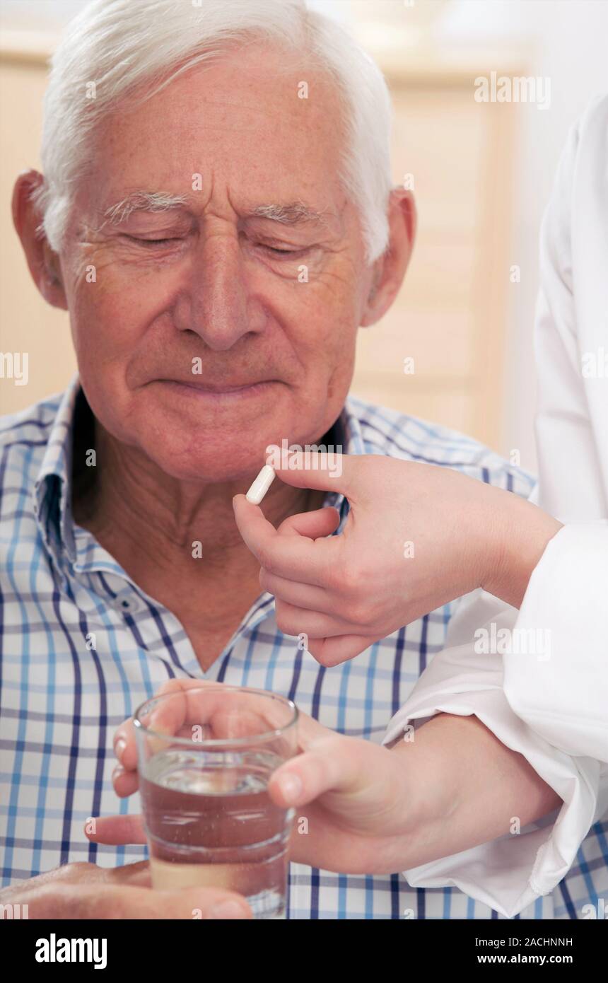 Geriatric care. Young woman helping an older man to take his medication ...