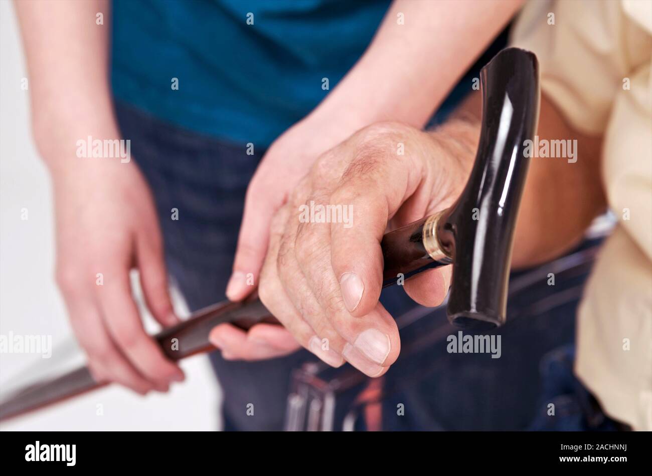 Geriatric care. Young woman helping an older man to use his walking ...