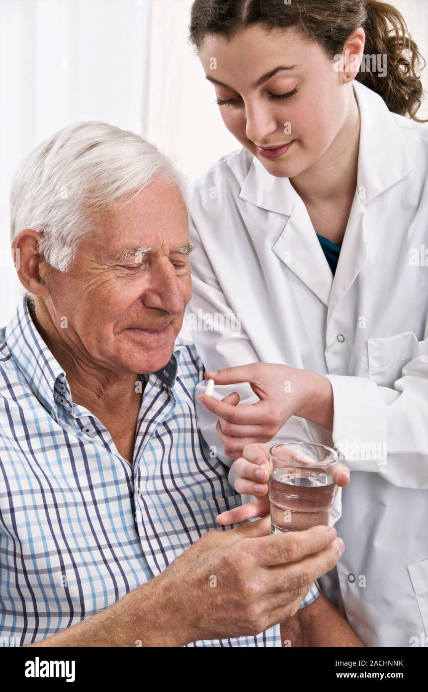 Geriatric care. Young woman helping an older man to take his medication ...