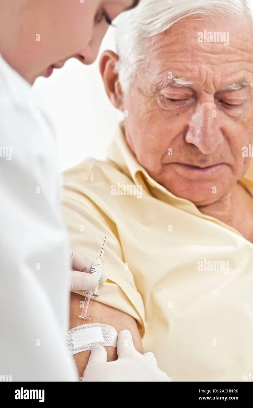 Geriatric care. Nurse putting a plaster on an older man's arm after giving him an injection ...