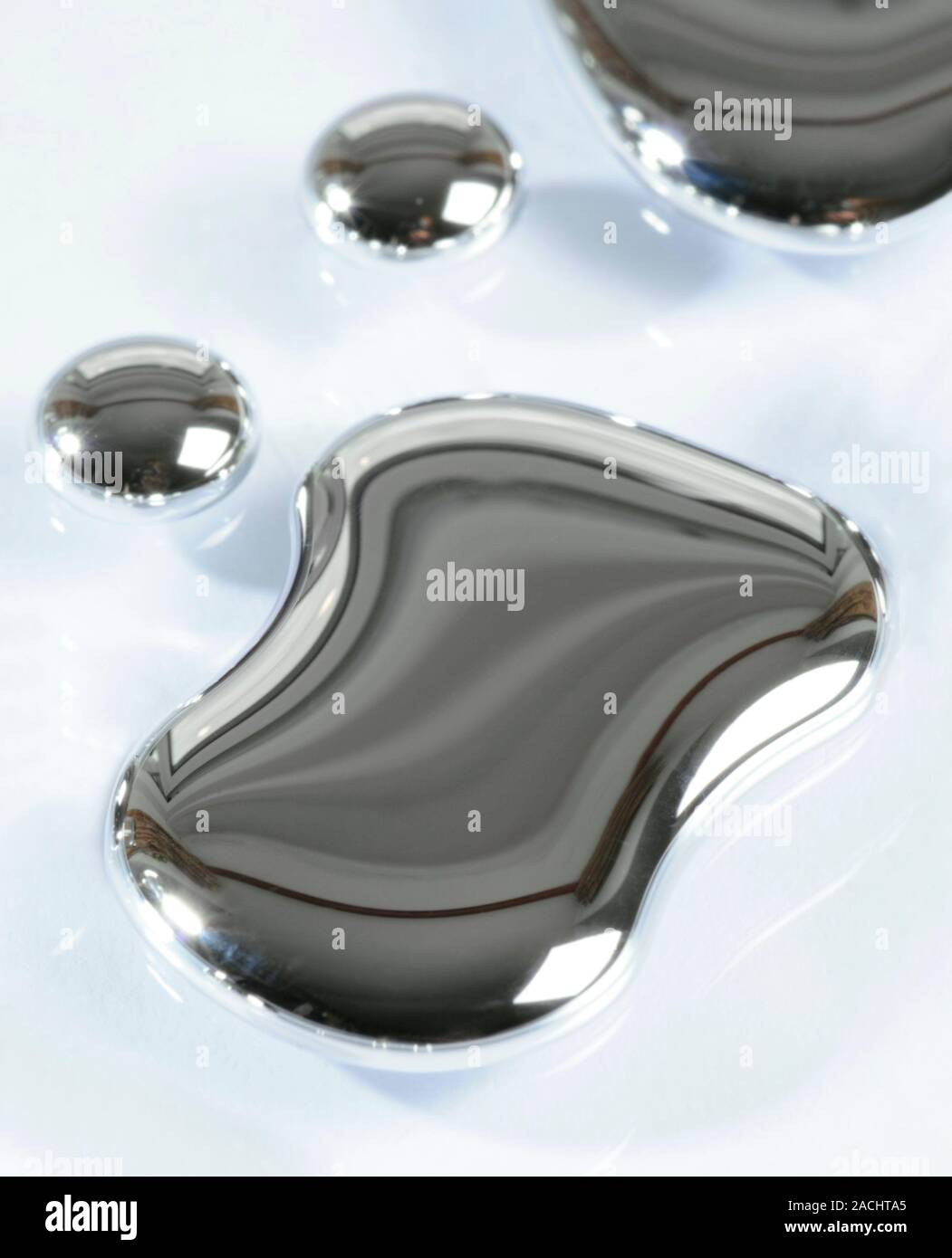 Drops of liquid mercury on a hard surface. Mercury has a very low ...