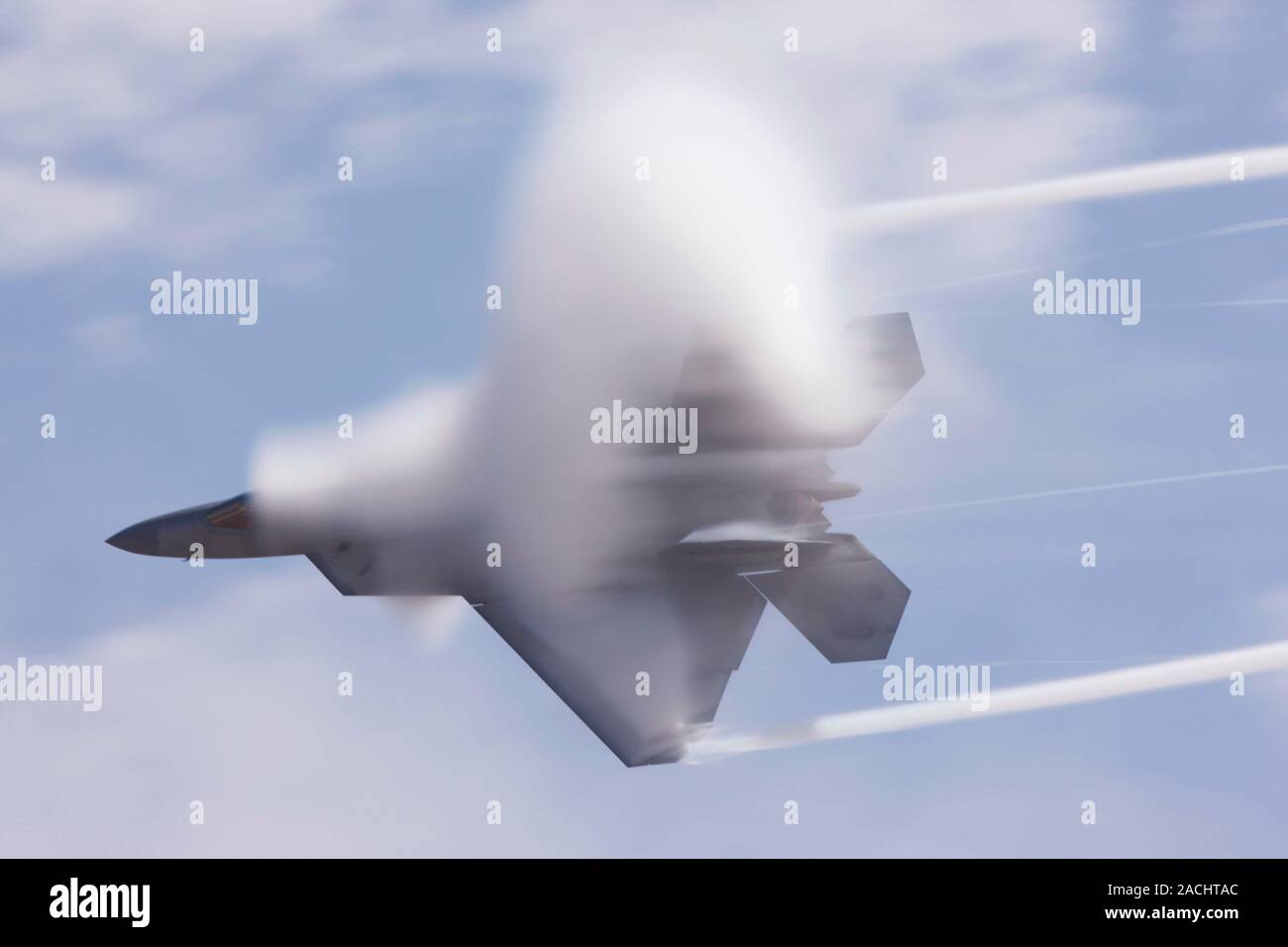 F-22 Raptor performing a high speed banking manoeuvre. Clouds have ...