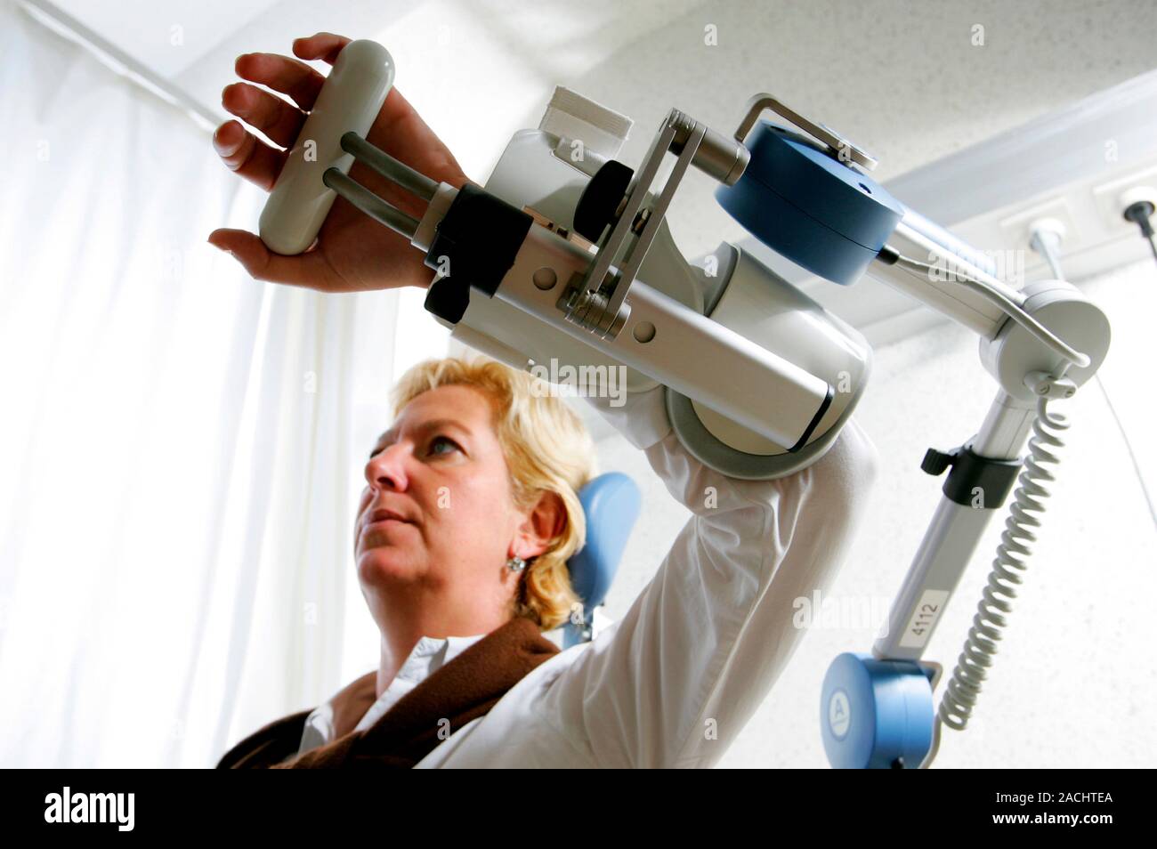 Physical therapy machine. Female patient with her arm in a motorised ...