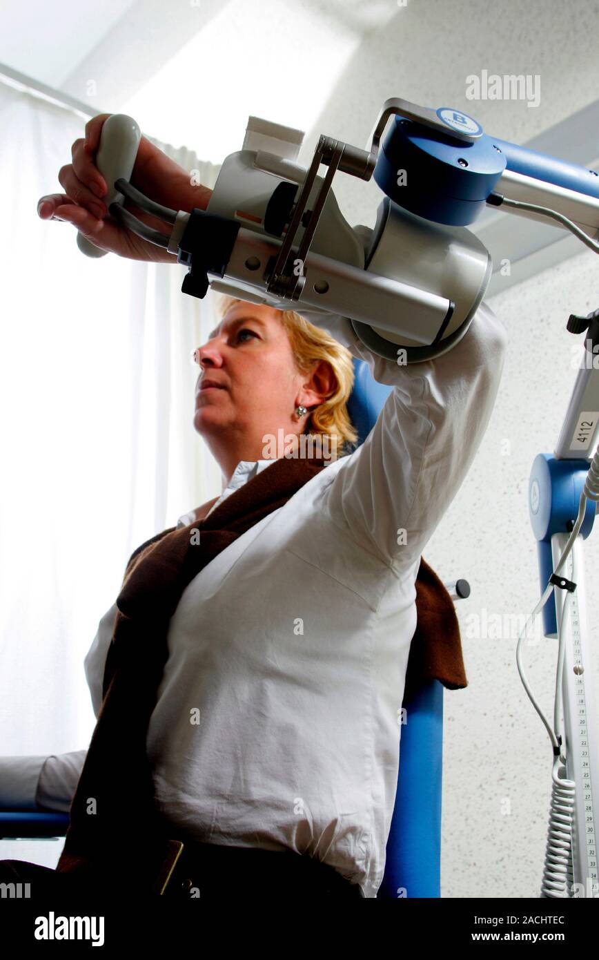 Physical therapy machine. Female patient with her arm in a motorised ...